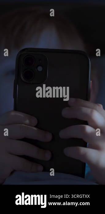 Close-up of unrecognisable little child lying in bed at night, holding ...