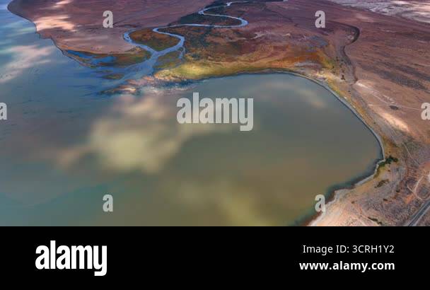 Narrow wavy river falling into the waterscape. Deserted land surround ...