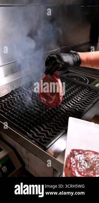 Chef places raw steak on a hot grill. Close-up of raw beef steak being ...