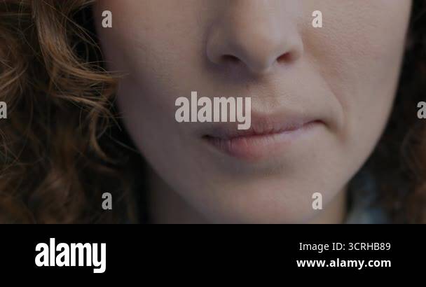 Close-up of female mouth while nervous anonymous woman biting and ...