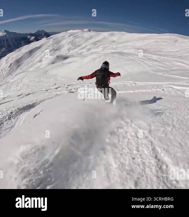 Snowboarder carving powder turns in slow motion on alpine mountain ...