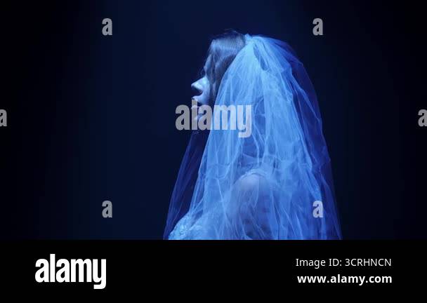 A dead bride, covered with a transparent veil, is illuminated by an ...