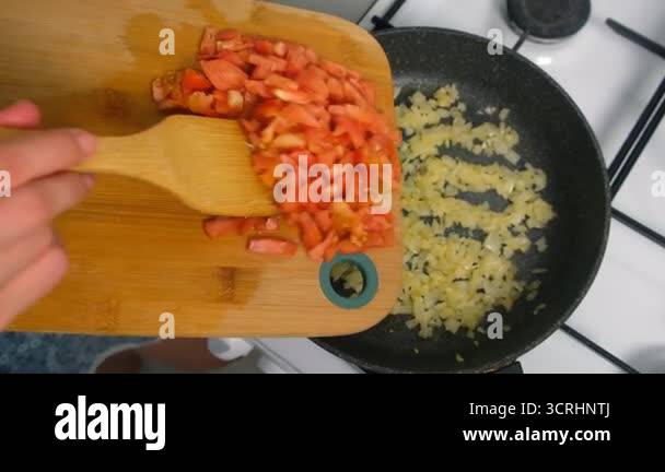 Chef woman cooking adding diced tomatoes into frying pan with fried ...