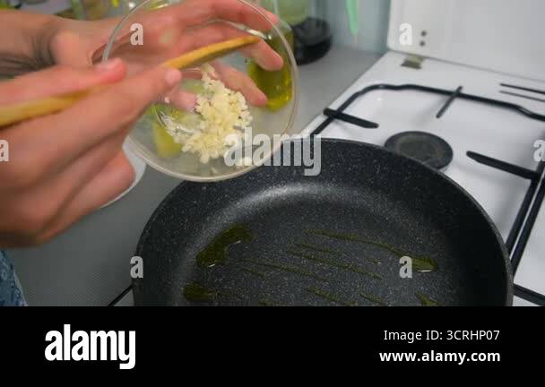 Chef woman hands cooking adding chopped garlic to frying pan on kitchen ...