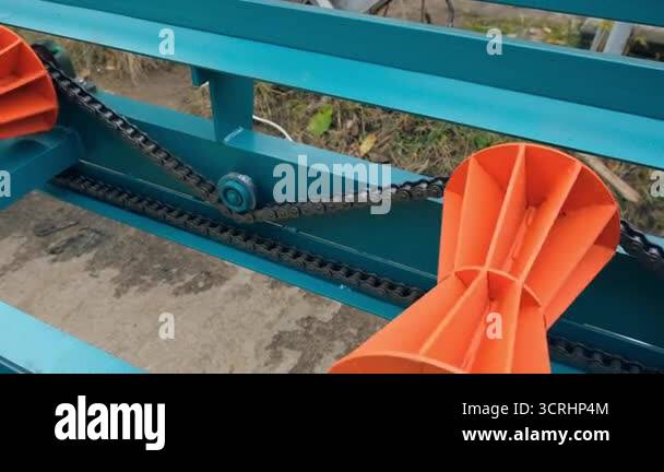 Chain conveyor belt moving along plastic orange rollers to move wooden ...