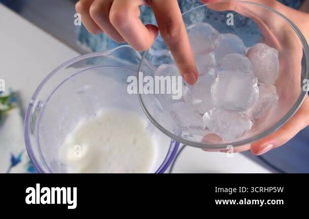 Woman putting ice pieces in blender preparing cooking white Brazilian ...