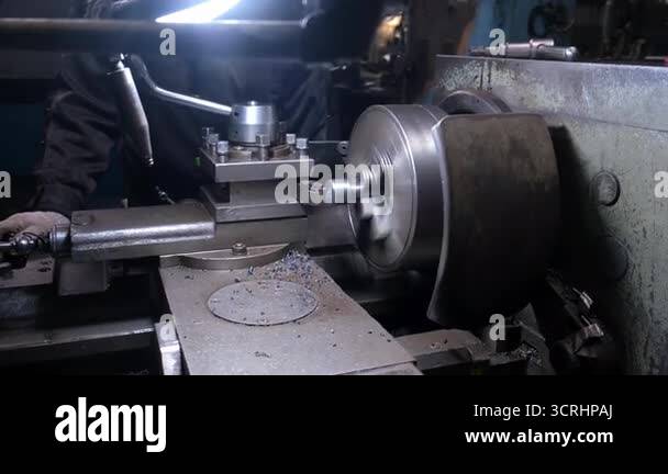 Metal worker operating working on lathe machine in workshop on factory ...