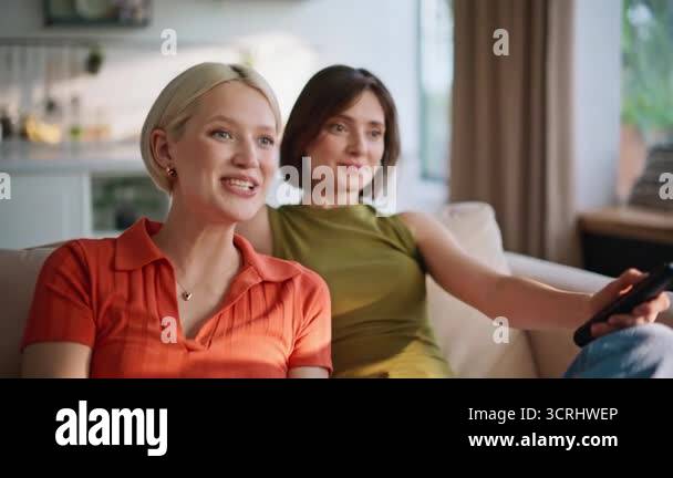 Two women watching television switching channels at domestic sofa ...
