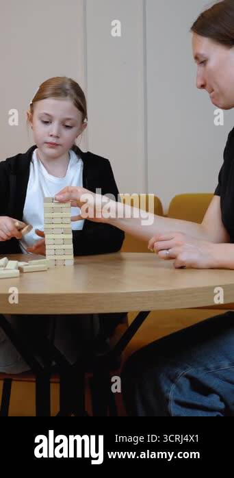 Family members carefully pulling wooden blocks from jenga tower ...