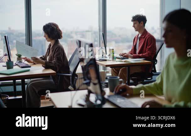 Laughing office employees working at open space workplace. Positive ...