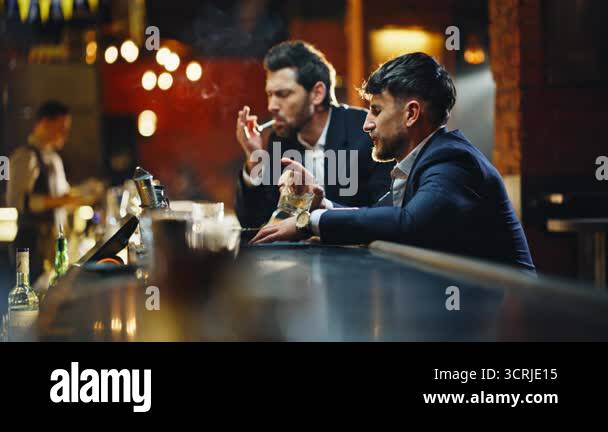 Closeup bar guests resting with alcohol and cigarettes at counter ...