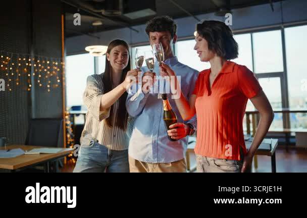 Joyful team clinking alcohol at corporate party in festive office ...
