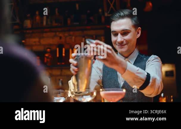 Closeup handsome barman using shaker making cocktail in bar. Smiling ...