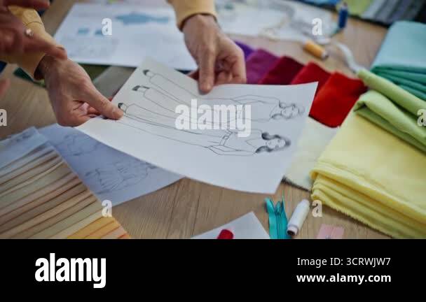 Dressmakers hands holding sketches with garment drawings planning new ...