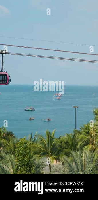 Modern cable car gondola ride over tropical seaside with fishing boats ...