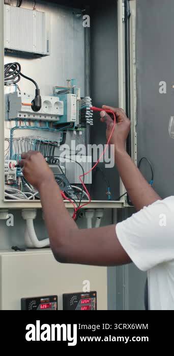 An electrician uses a multimeter to test an electrical panel, ensuring ...