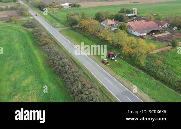 Above view, two tractors as they are pulling grass cutting machine over ...