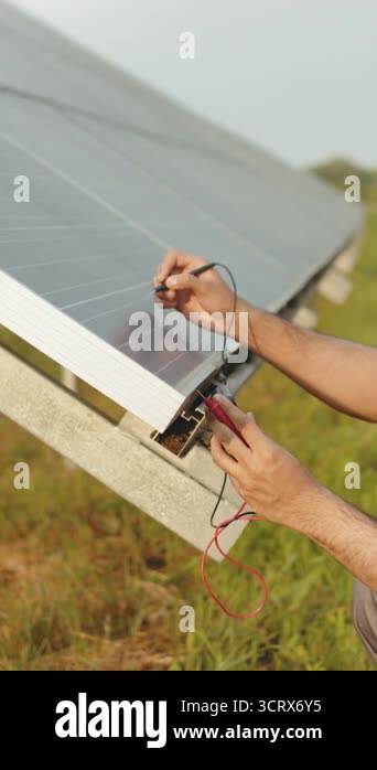 A technician inspects a solar panel with a multimeter, ensuring optimal ...