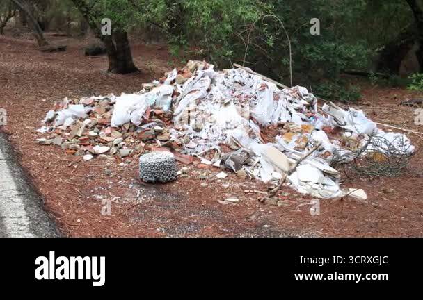 Construction debris and garbage polluting a roadside area, highlighting ...