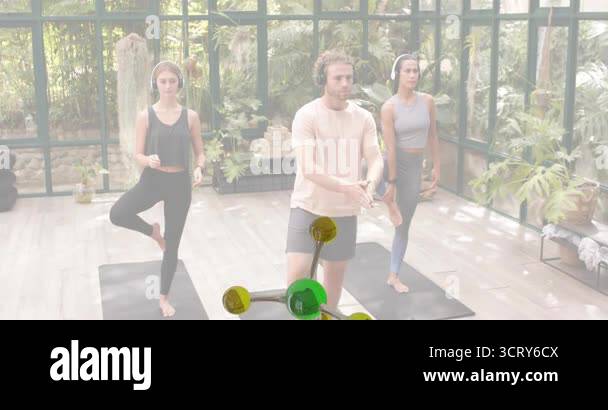 instructor guiding students balancing on mats in yoga studio as ...