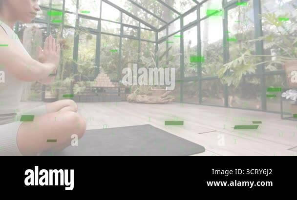 woman kneeling on yoga mat in greenhouse forming mudra while digital glitch growing for health ...