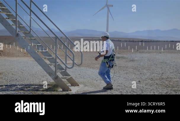 Technician gripping handrail and securing safety lanyard starting climb ...