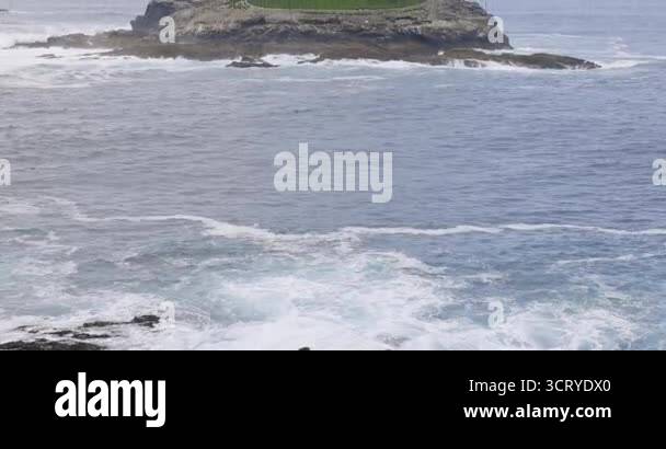 Lighthouse at seaside in Cornwall at Godrevy point with waves and rocks ...