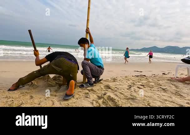 Two people digging sand on a beach Stock Video Footage - Alamy