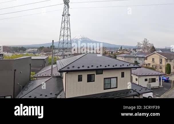 A serene view of Mount Fuji with rooftops and power lines in ...