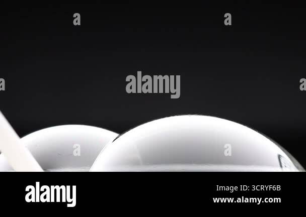 A wand interacts with soap bubbles, creating reflections and colors ...