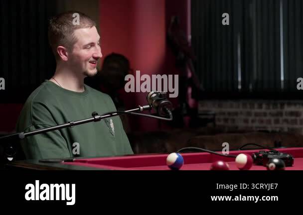 A man engages in a podcast recording session next to a pool table, with ...