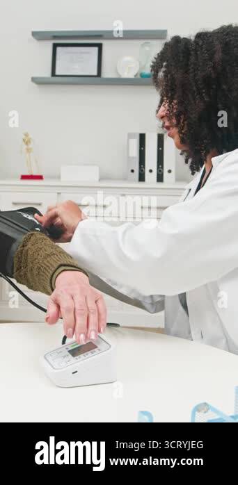 A professional African American doctor measures a senior patients blood ...