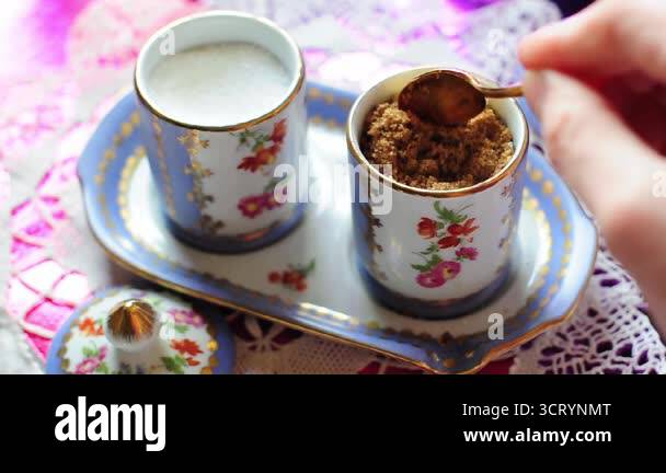 Dainty hand holding a small golden spoon swirls together brown and ...