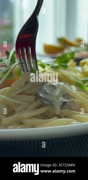 woman eating pasta spaghetti outside in park, next to columns or ...