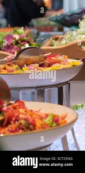 Vertical screen woman serving fresh colorful salads at elegant buffet ...
