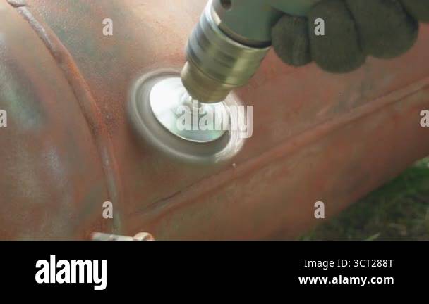 Electric drill with wire brush attachment polishing rusty metal surface ...