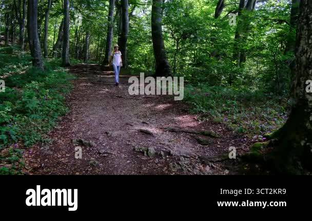 Woman hiking with backpack through a lush forest, enjoying the natural ...