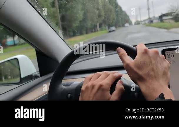 POV shot of a man driving a modern electric vehicle on a suburban ...