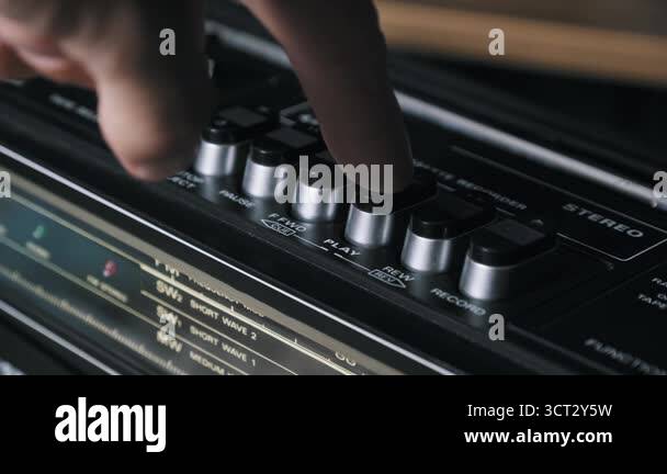 Wider angled view of hand operating vintage ghetto blaster, pressing ...