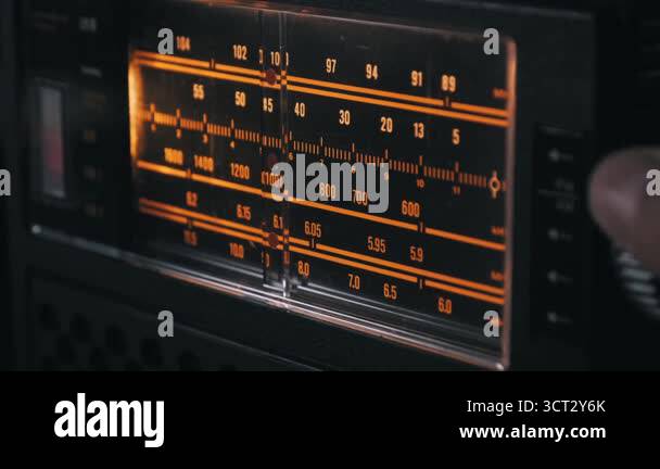 Side view of hand turning tuning knob on old radio receiver, searching ...