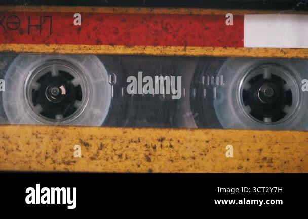 Extreme close-up on spinning reels of a grungy audio cassette, showing ...