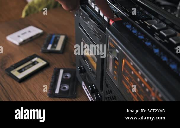 Close-up of hand pressing eject button on black retro boombox, removing ...