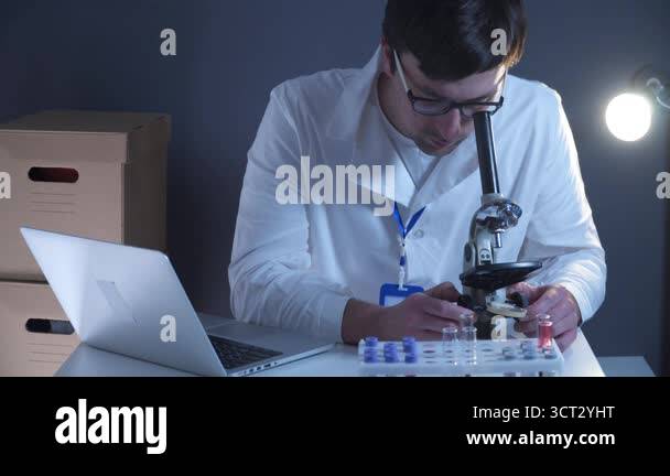 Scientist in lab coat and eyeglasses working at workplace with laptop ...