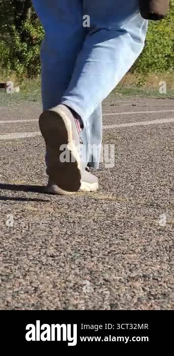 Vertical low-angle shot of two people walking away on asphalt path ...