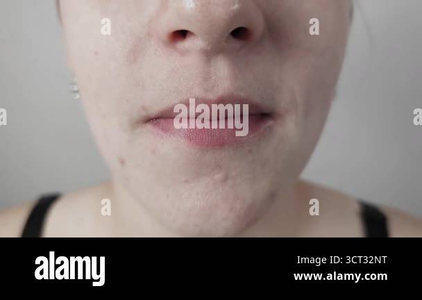 Extreme close-up of a young womans mouth as she licks her glossy lips ...