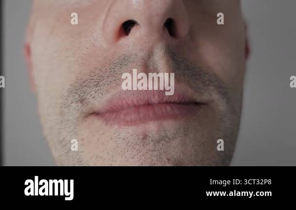 Extreme close up of an unshaven male face, lips curling into a slow ...