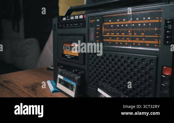 Medium shot of black vintage boombox playing audio cassette, showing ...