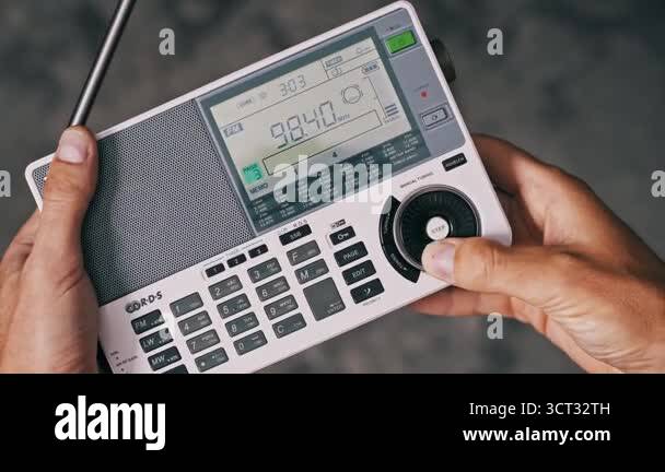 Close-up top-down view of male hands tuning a white digital radio ...