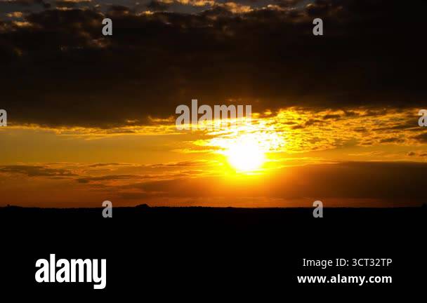 Wide-angle timelapse shows a brilliant sun setting behind heavy, dark ...