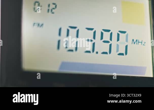 Close-up of digital radio display scanning FM frequencies downward ...